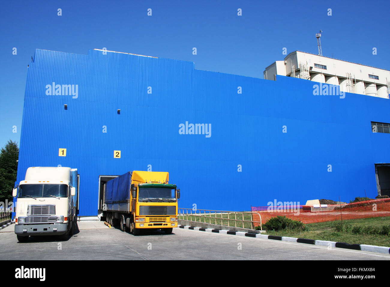 Two lorries on a background of a dark blue warehouse Stock Photo - Alamy