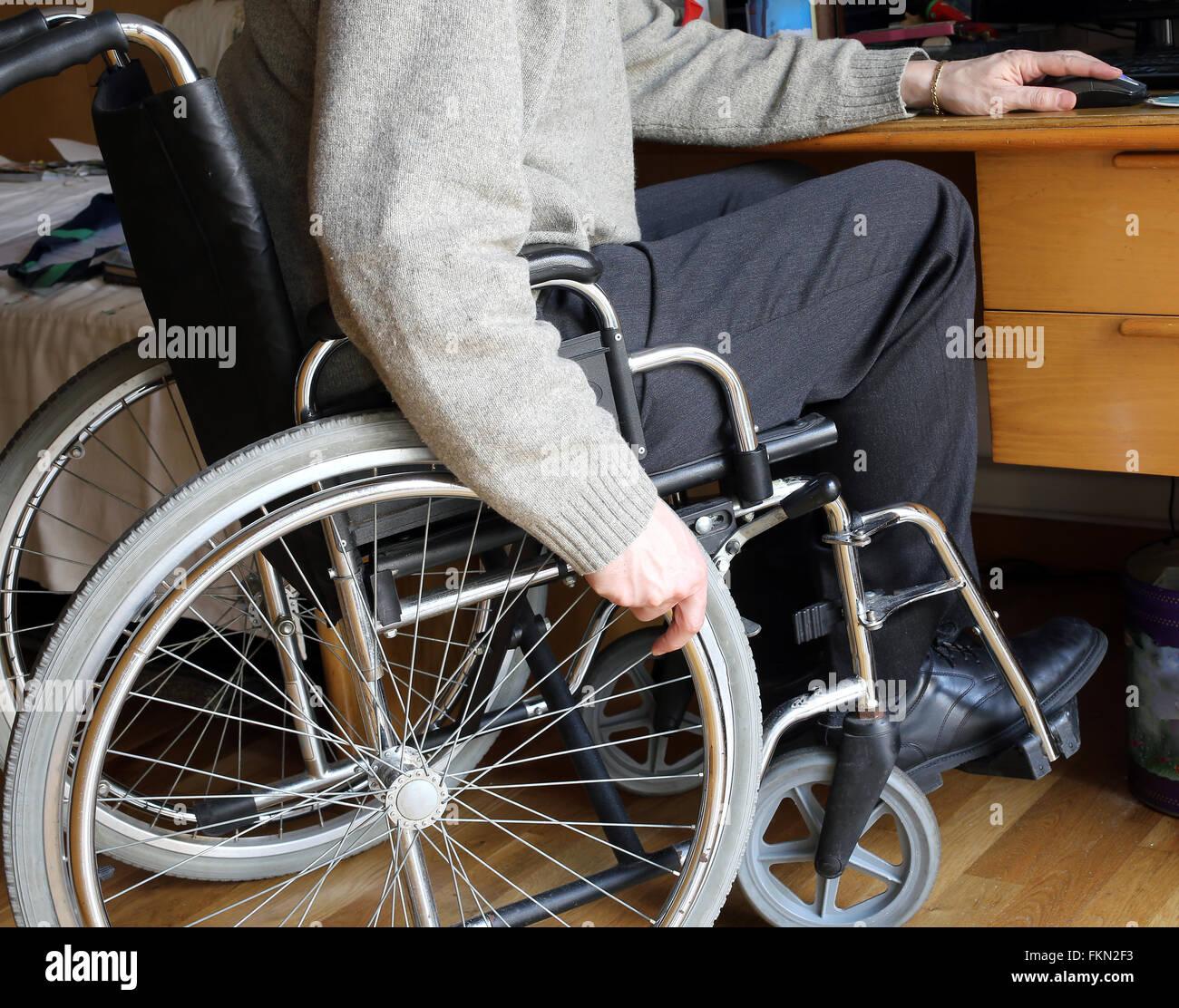 person sitting in a wheelchair at a desk with mouse and pc Stock Photo ...