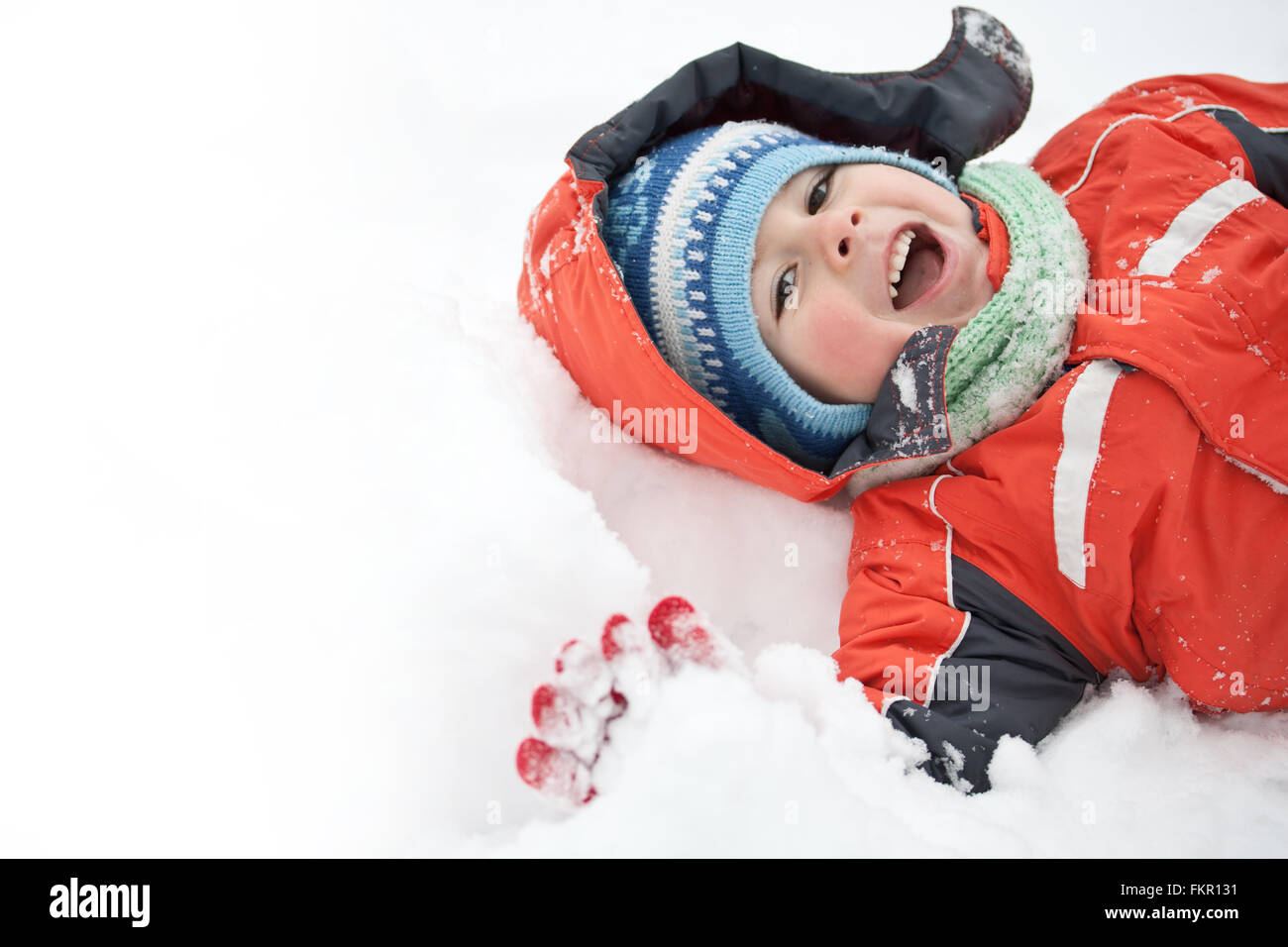Portrait of little happy boy lies in snow Stock Photo - Alamy