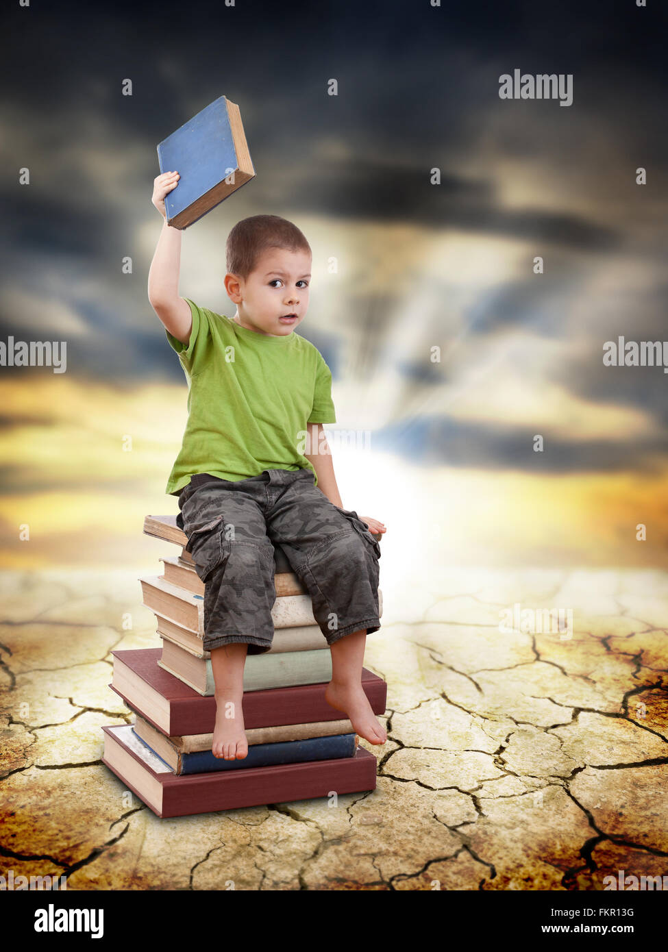 Child sitting on a stack of books and hold a book in hand, sunrise in ...