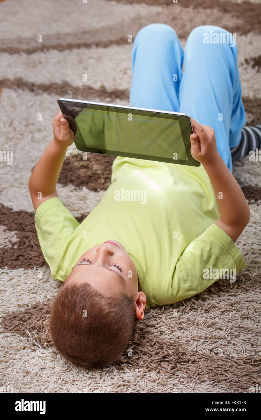 Child holding digital tablet, lying on a carpet Stock Photo - Alamy