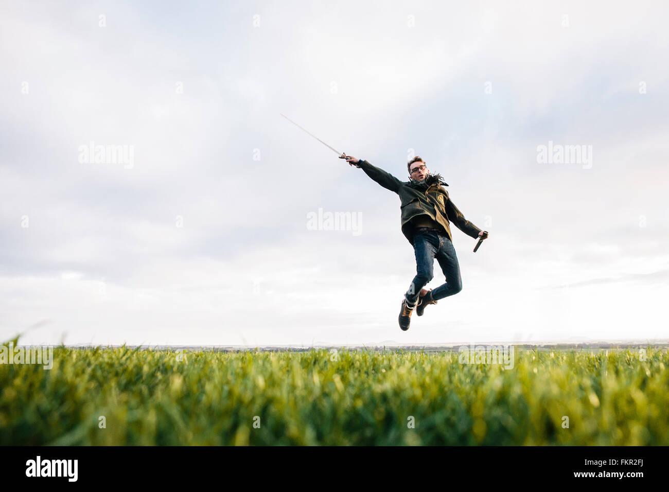 Caucasian man unsheathing sword in field Stock Photo - Alamy