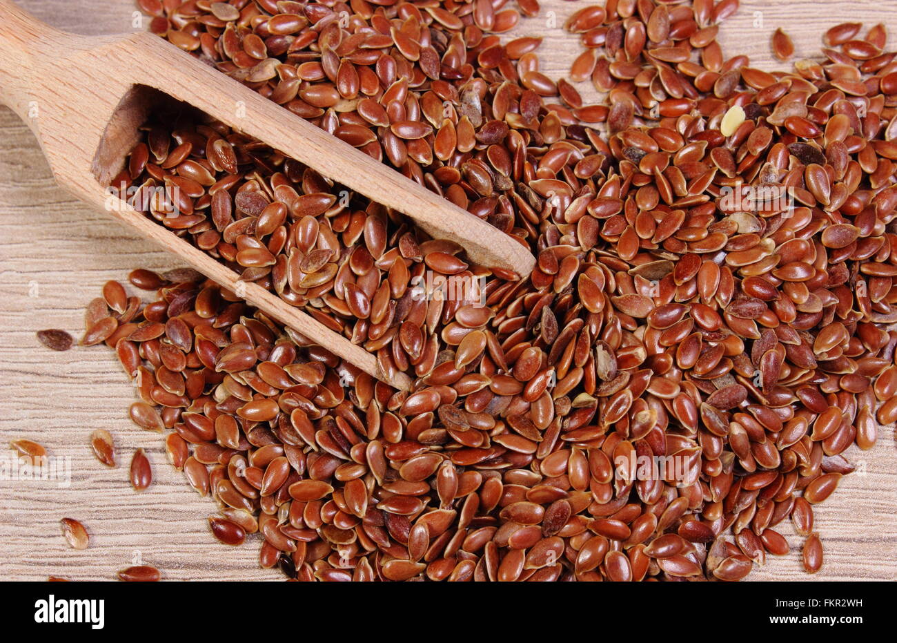 Heap of brown linseed, flax seeds with wooden spoon on wooden background, concept for healthy ...