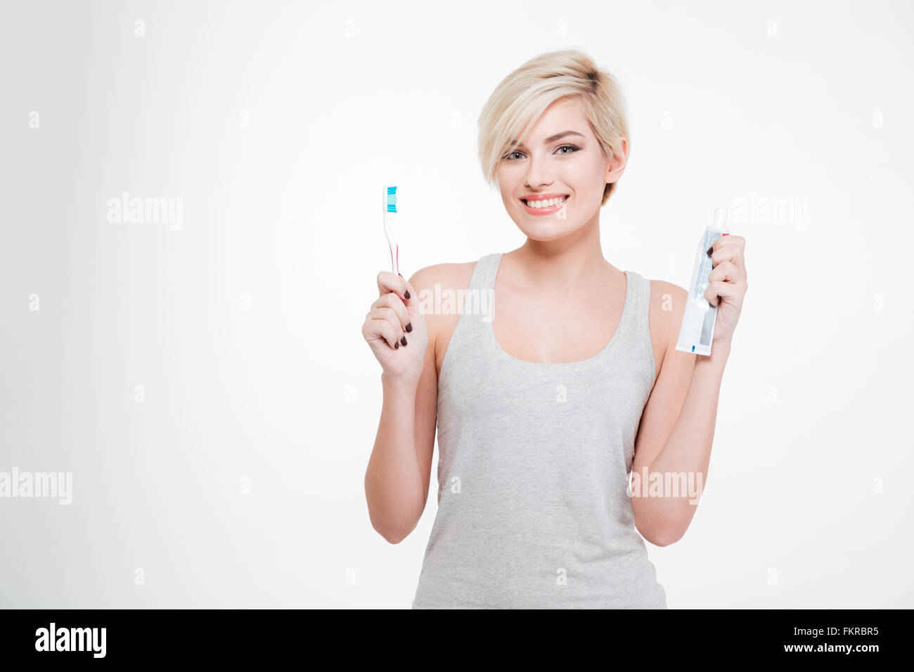Portrait of a happy blonde woman holding toothbrush and toothpaste ...