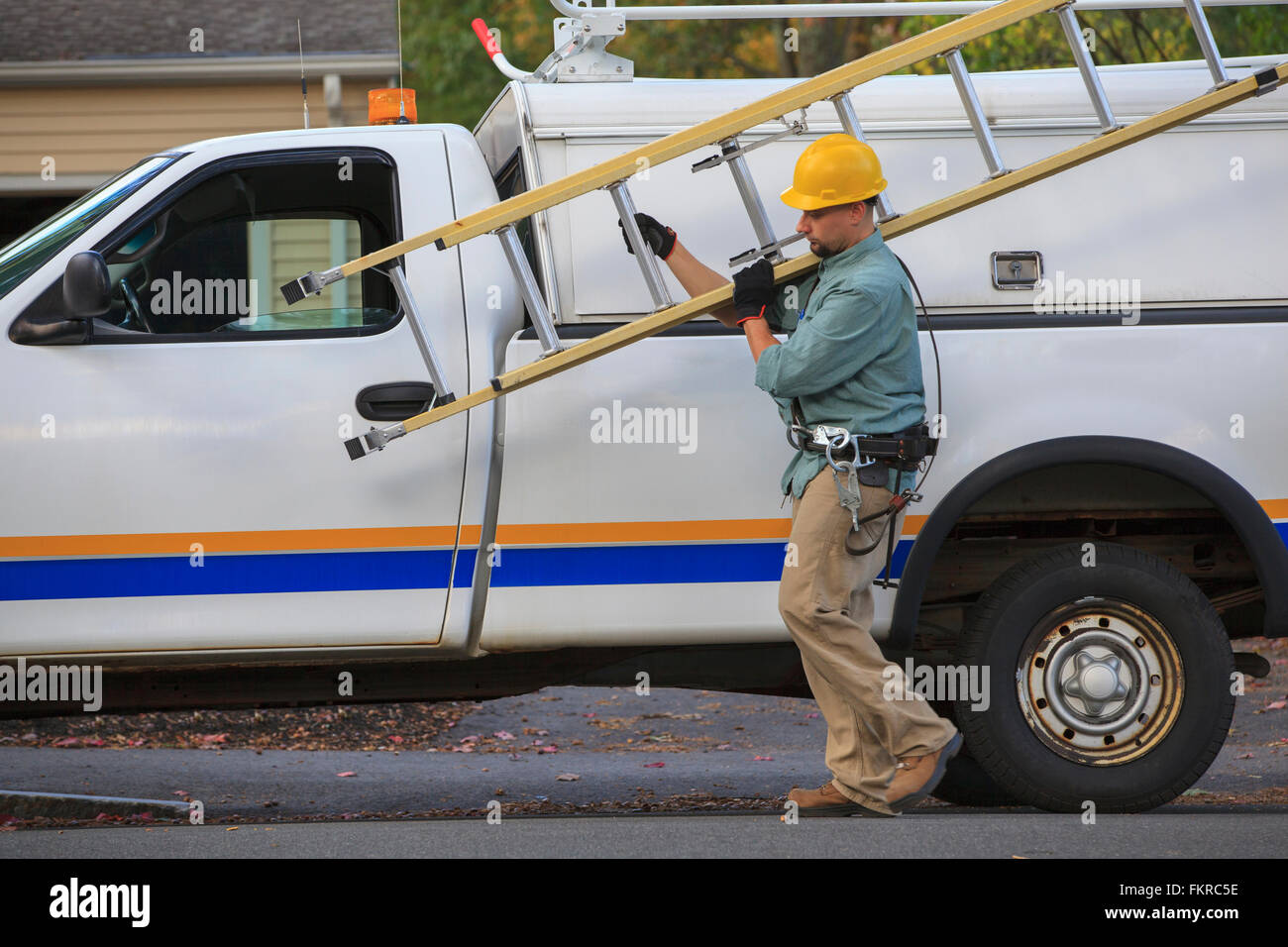 Caucasian worker carrying ladder near truck Stock Photo - Alamy