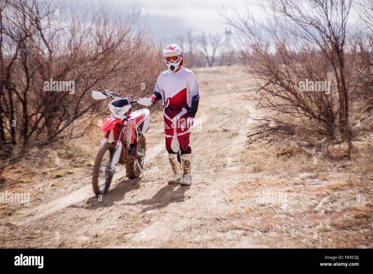 Dirt bike rider standing with motorcycle in rural field Stock Photo - Alamy
