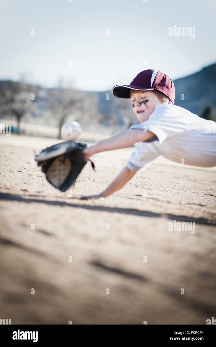 Caucasian boy catching baseball on field Stock Photo - Alamy