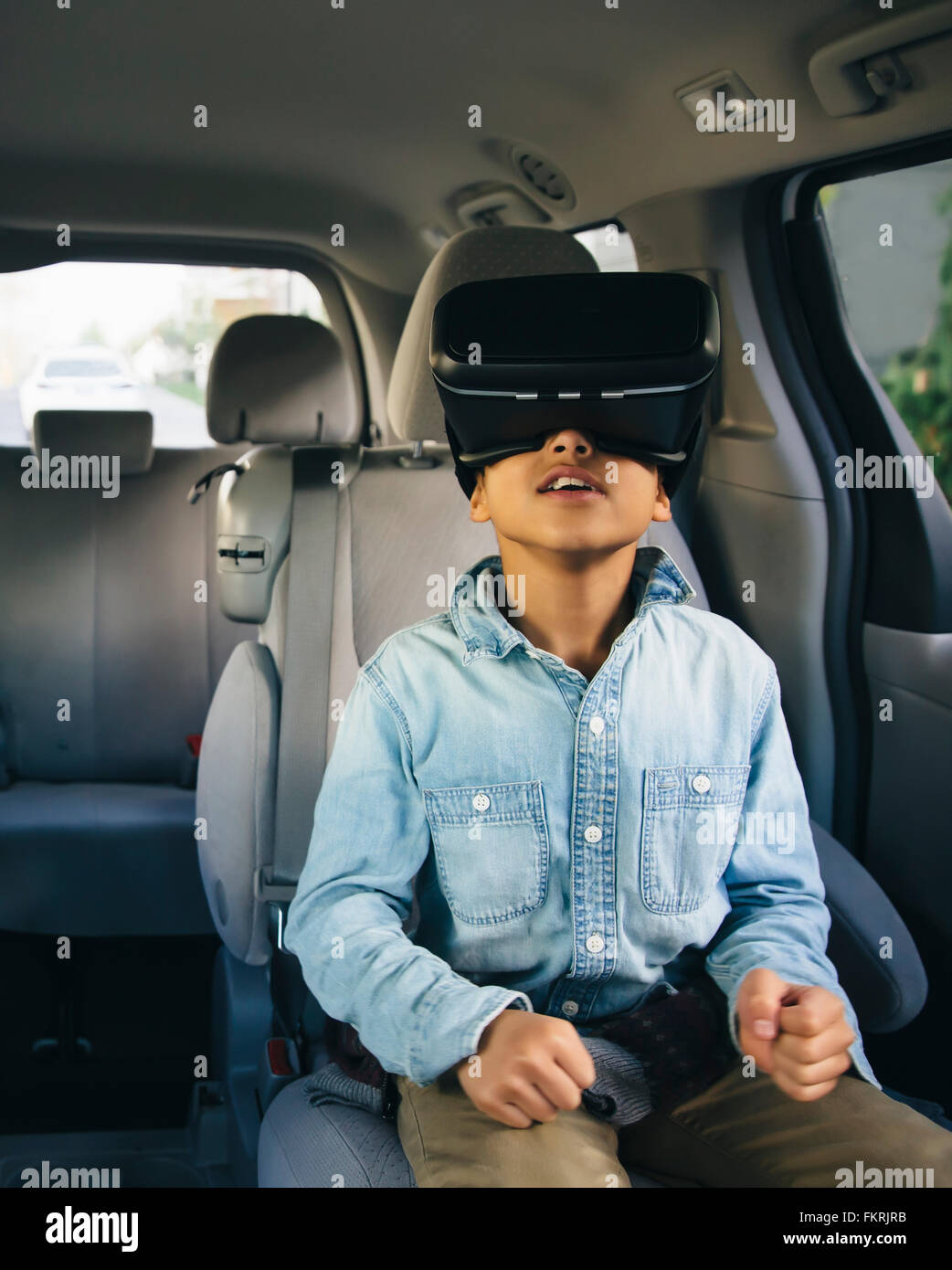 Mixed race boy using virtual reality goggles in car Stock Photo - Alamy