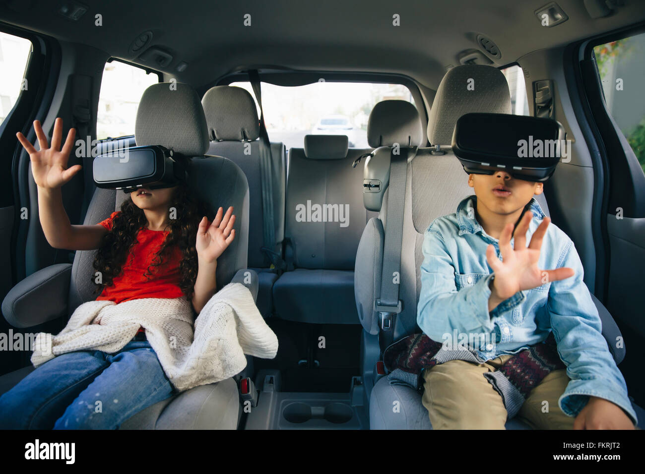 Mixed race children using virtual reality goggles in car Stock Photo ...