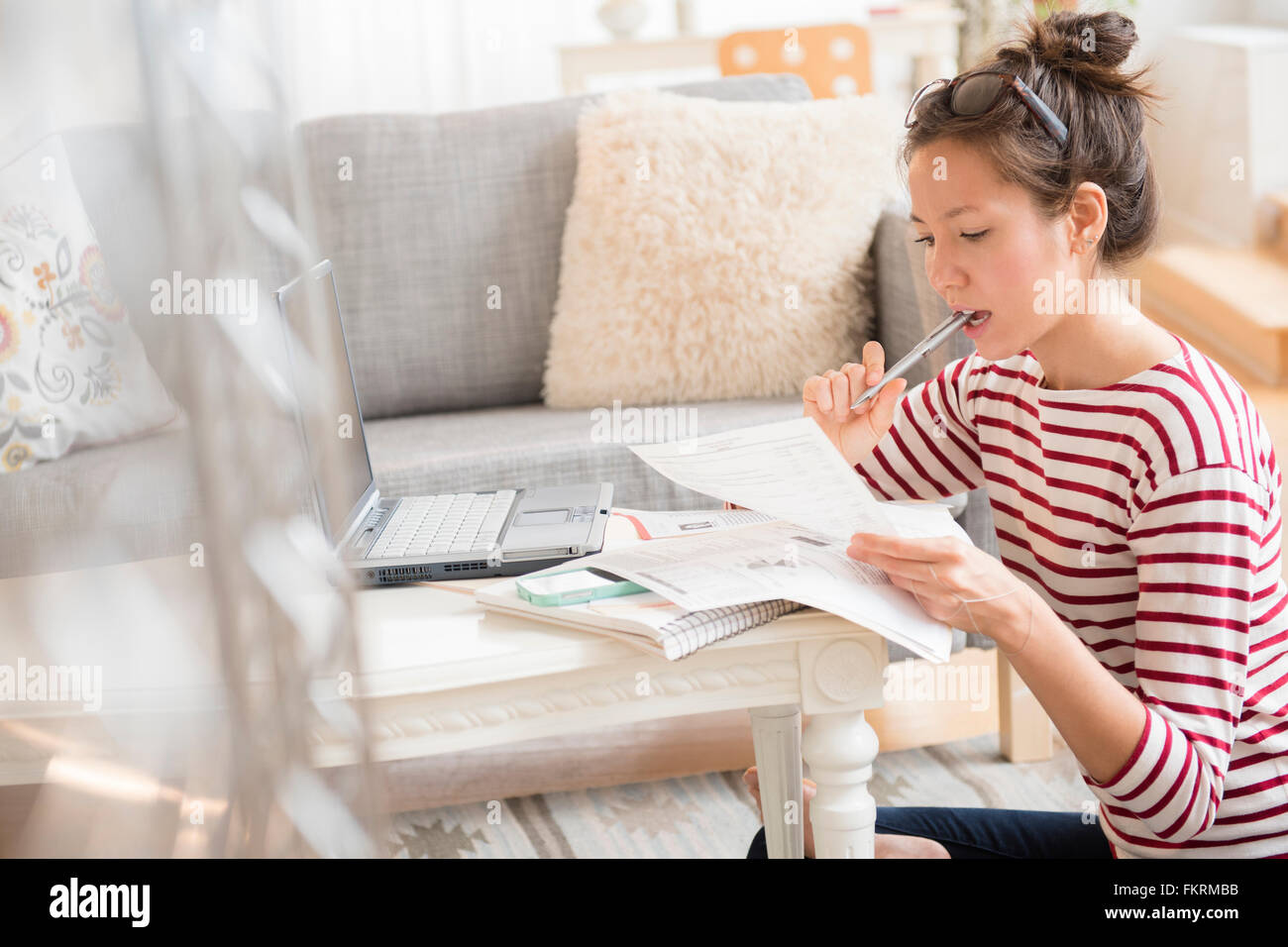 Mixed race woman paying bills on laptop Stock Photo - Alamy