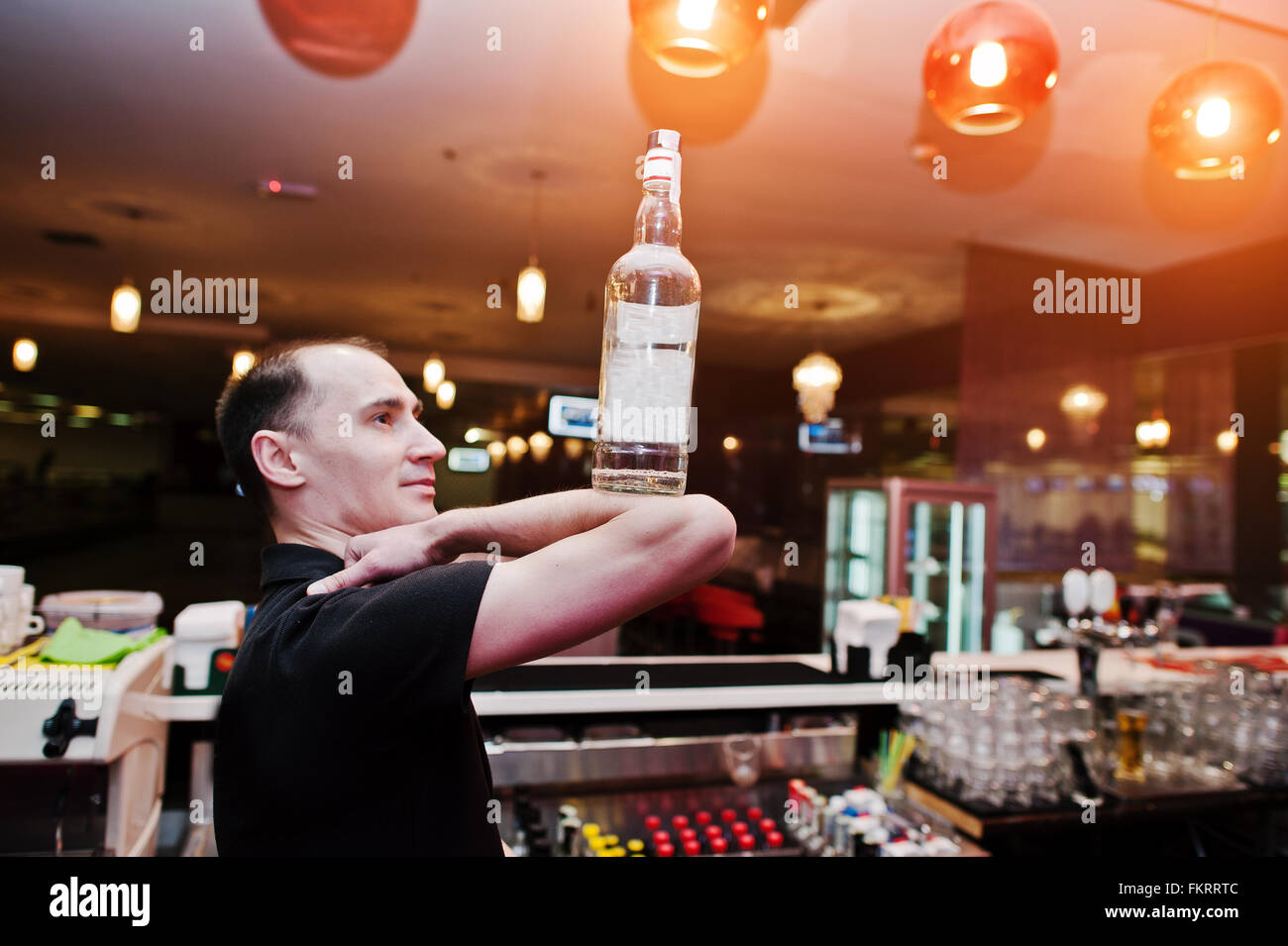 Barman hold bottle on elbows of hand at the bar Stock Photo - Alamy