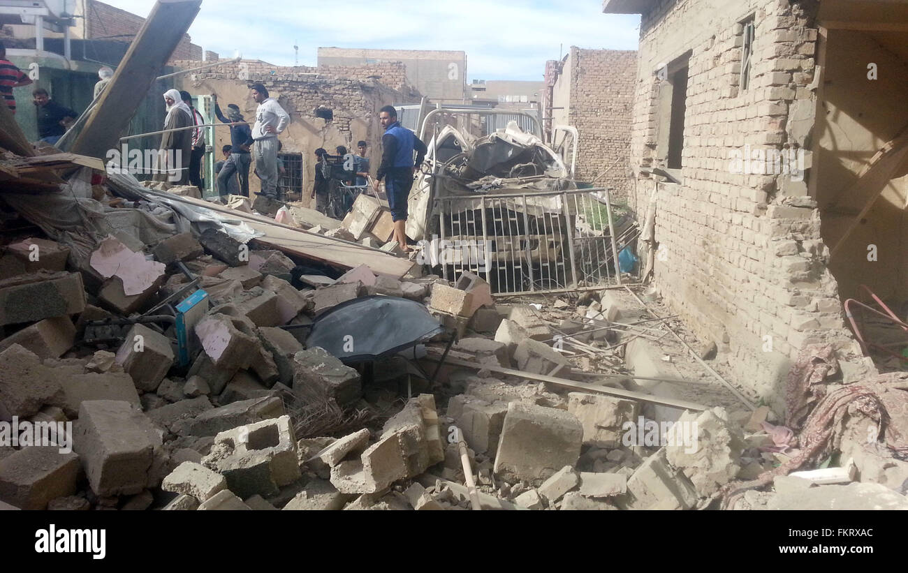 Fallujah, Iraq. 9th Mar, 2016. People stand by a destroyed building ...