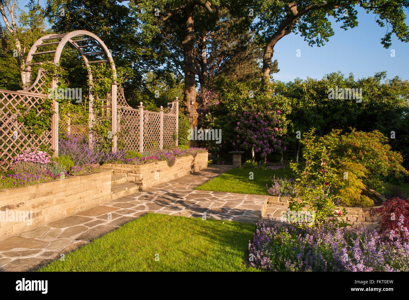 Sunlit path, flowering plants, wall, steps, trellis arch & screen ...
