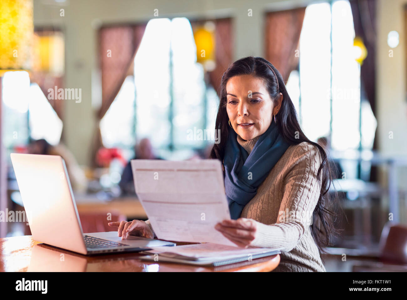 Hispanic woman paying bills on laptop in cafe Stock Photo - Alamy