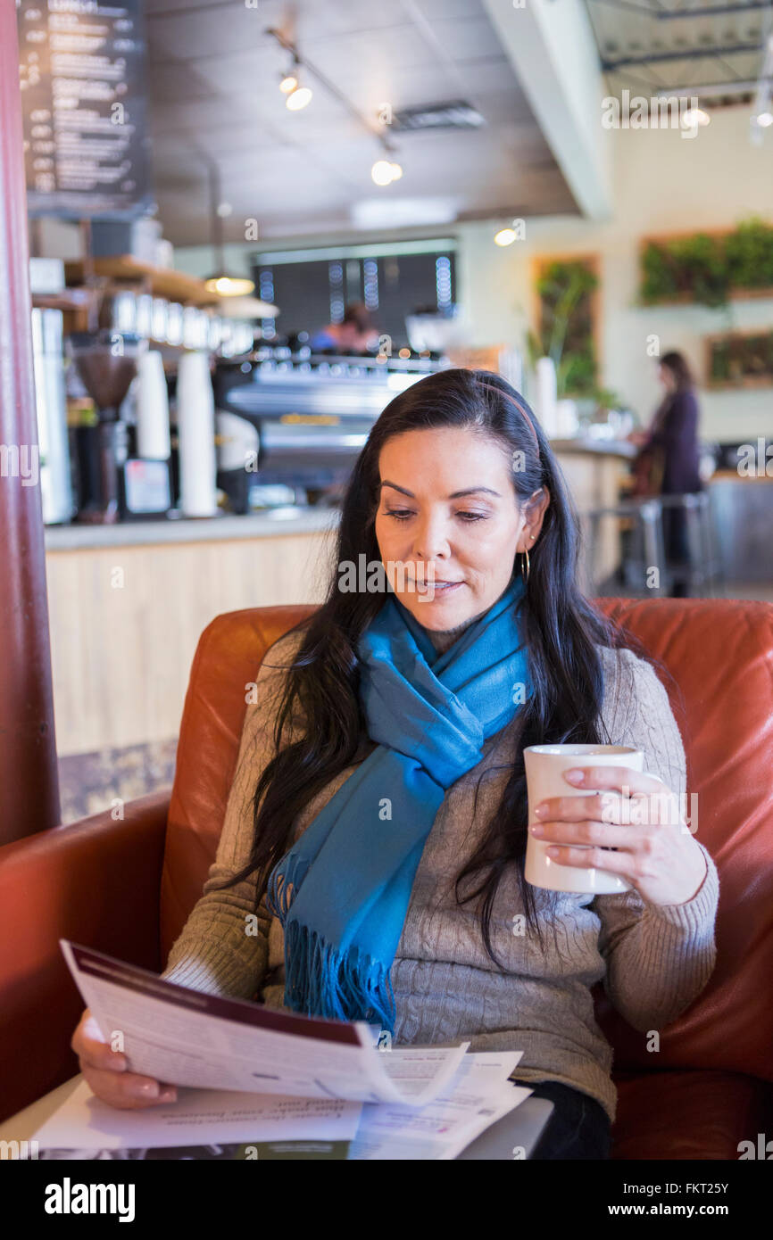 Hispanic woman reading paperwork in cafe Stock Photo - Alamy