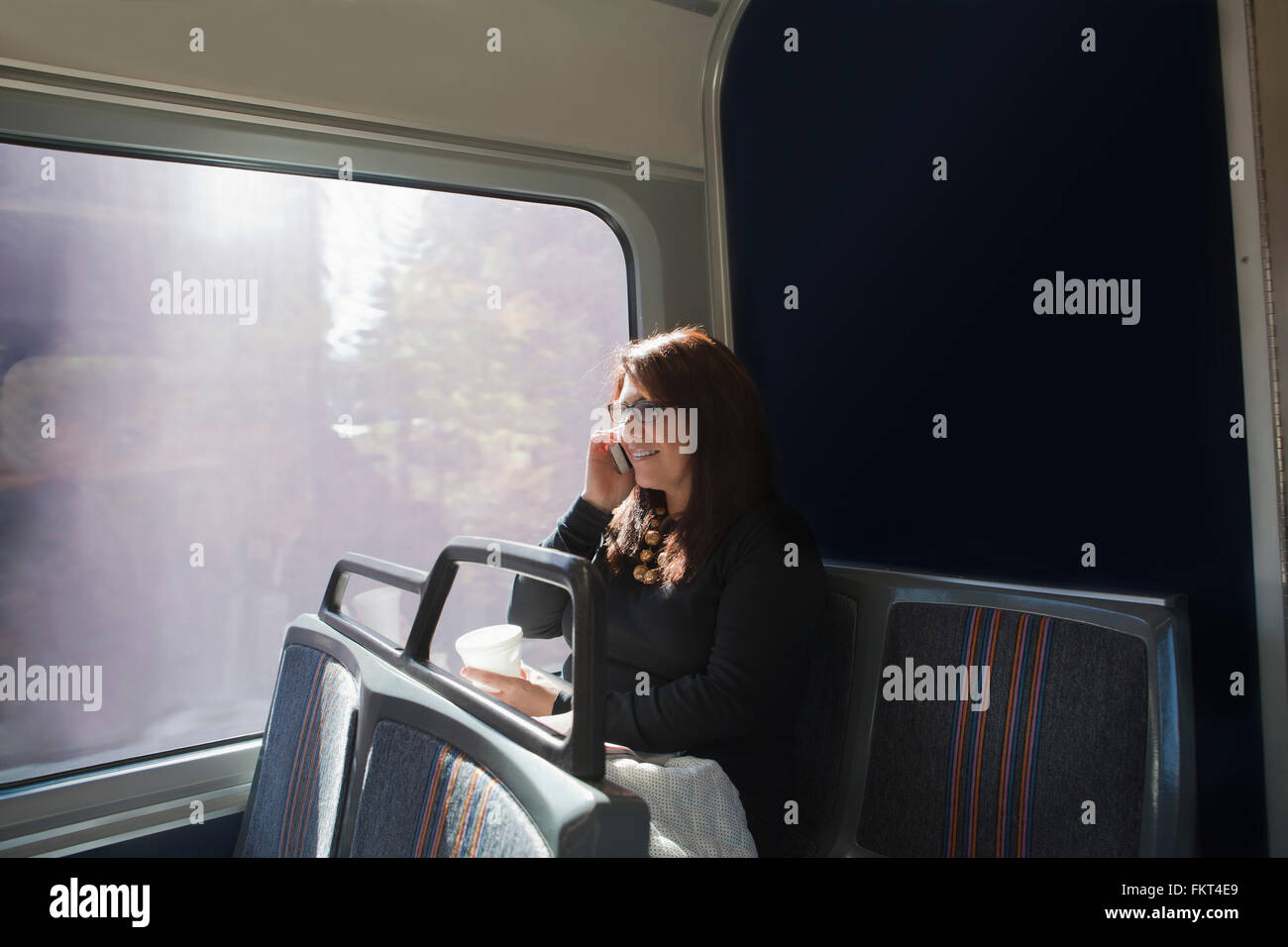 Hispanic woman talking on cell phone on train Stock Photo - Alamy
