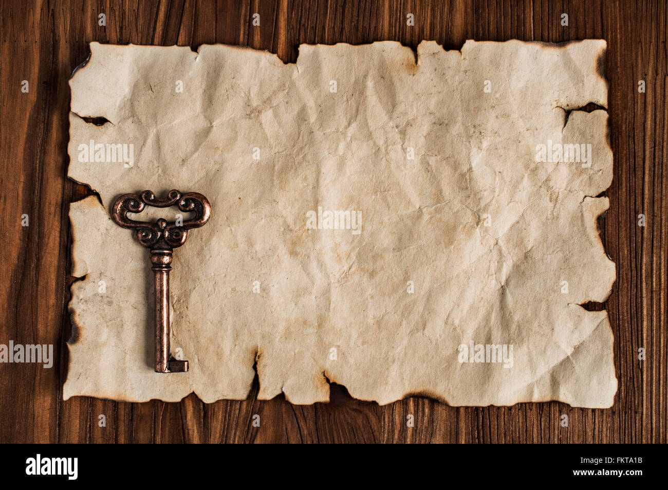 Sheet of ancient parchment or old paper and vintage key on wooden ...