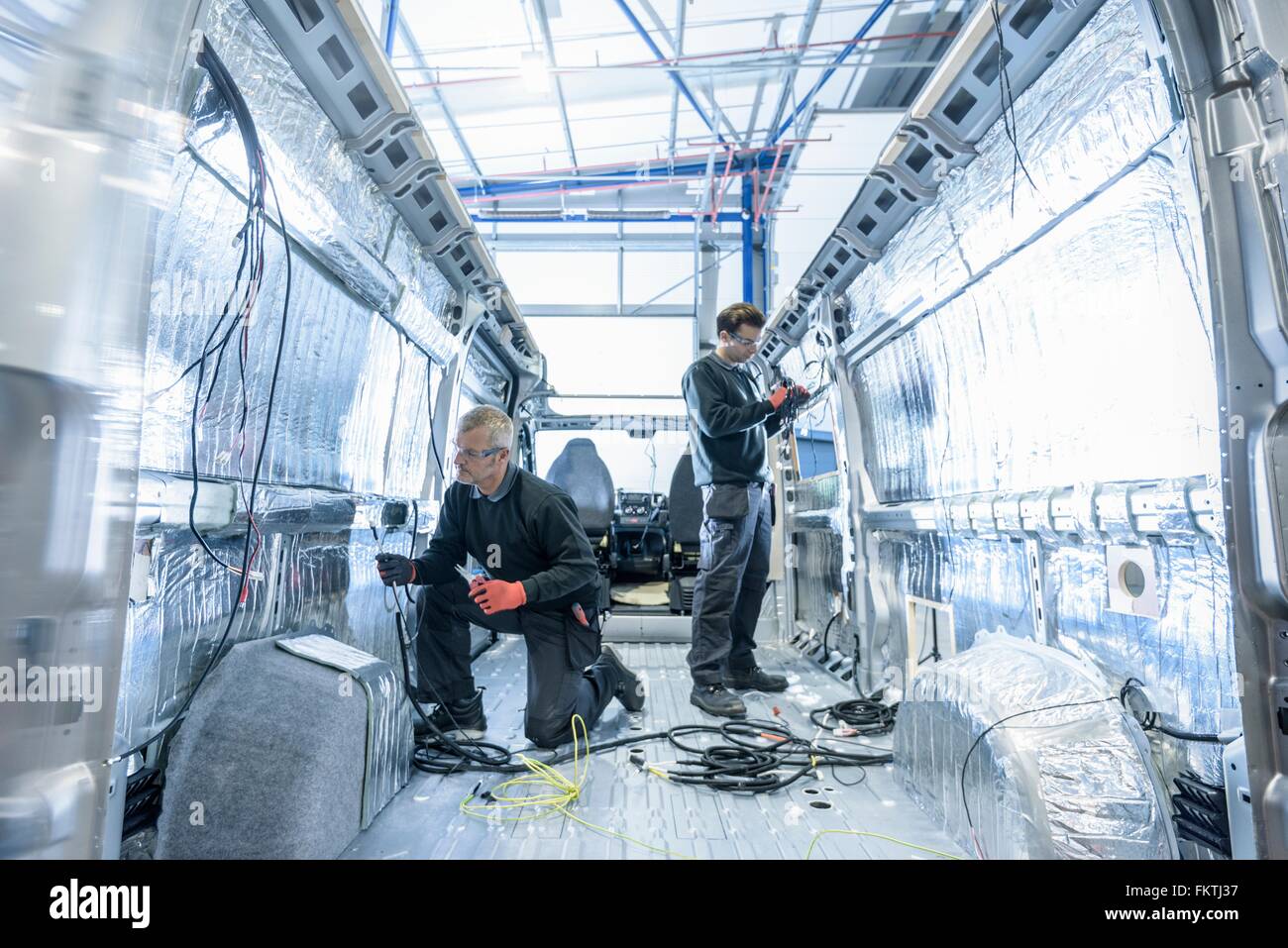 Workers fitting electrics on motorhome production line Stock Photo - Alamy