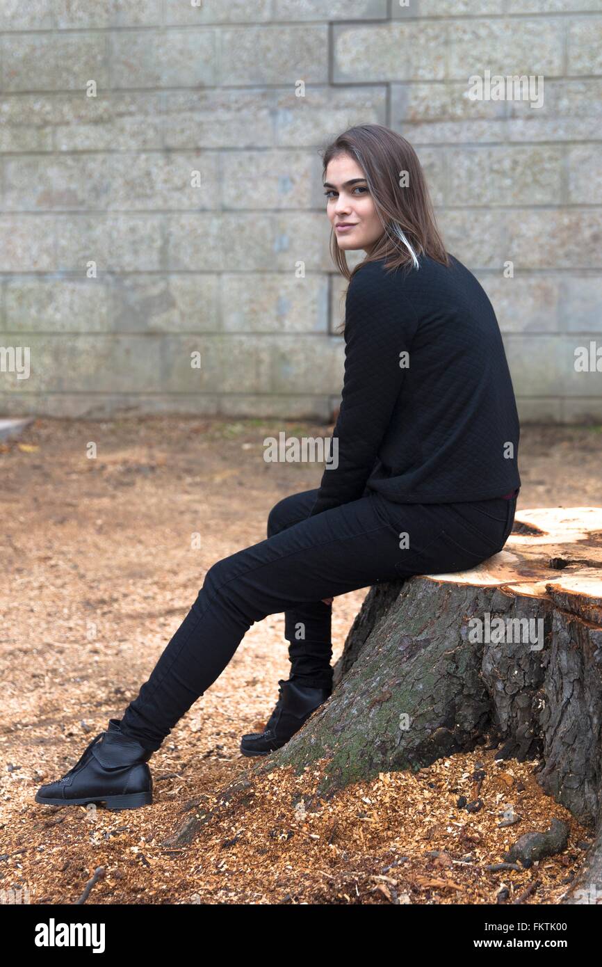 Young woman sitting on tree stump Stock Photo - Alamy