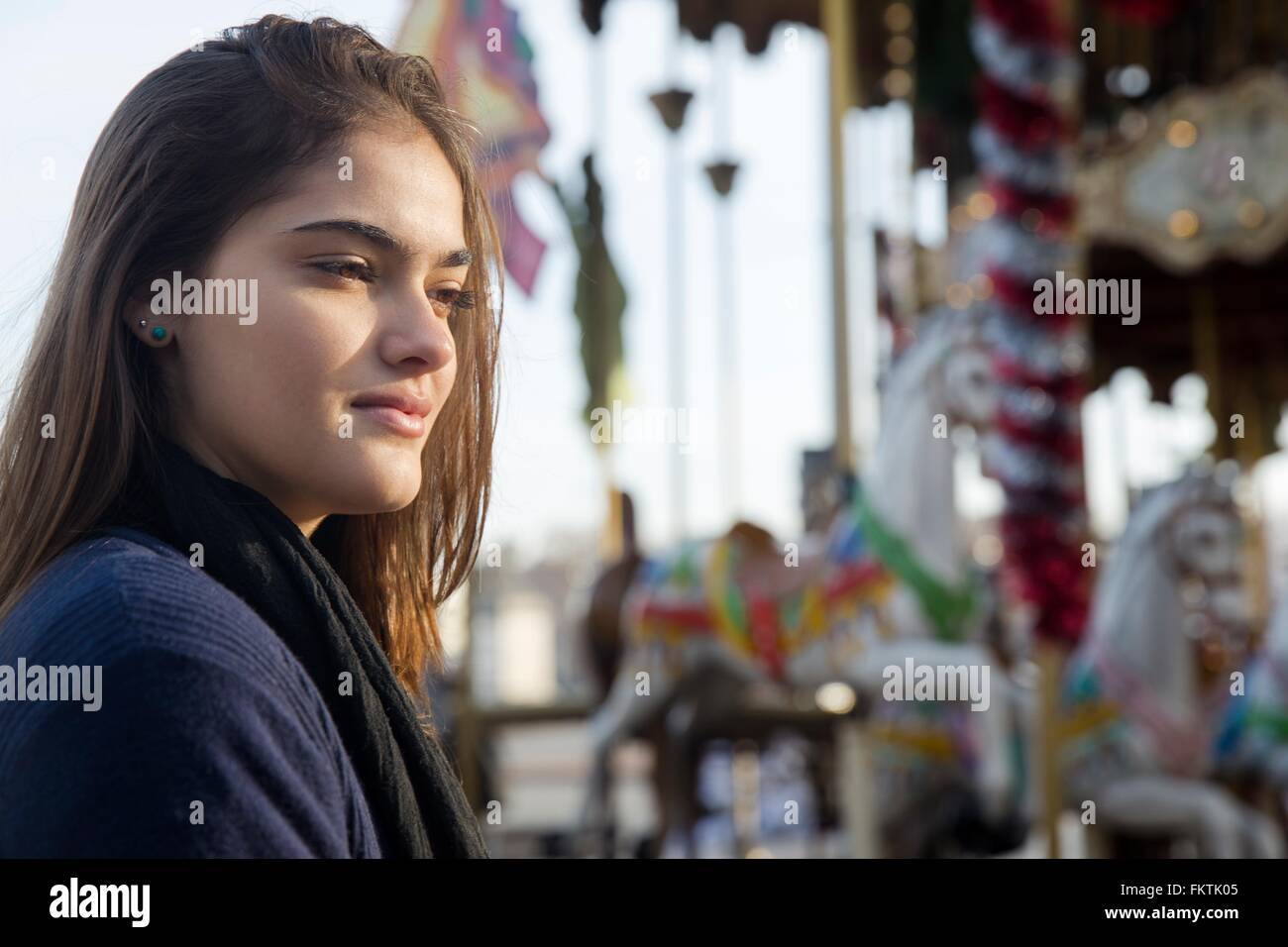 Side view of young woman, carousel in background Stock Photo - Alamy