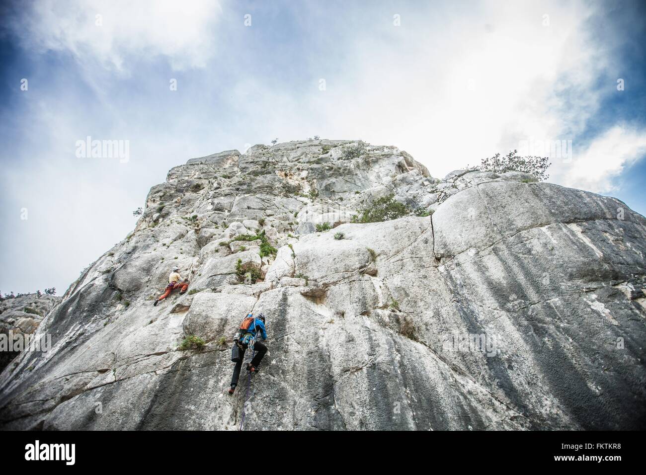 Low angle rear view rock climber climbing up mountainside, Ogliastra ...