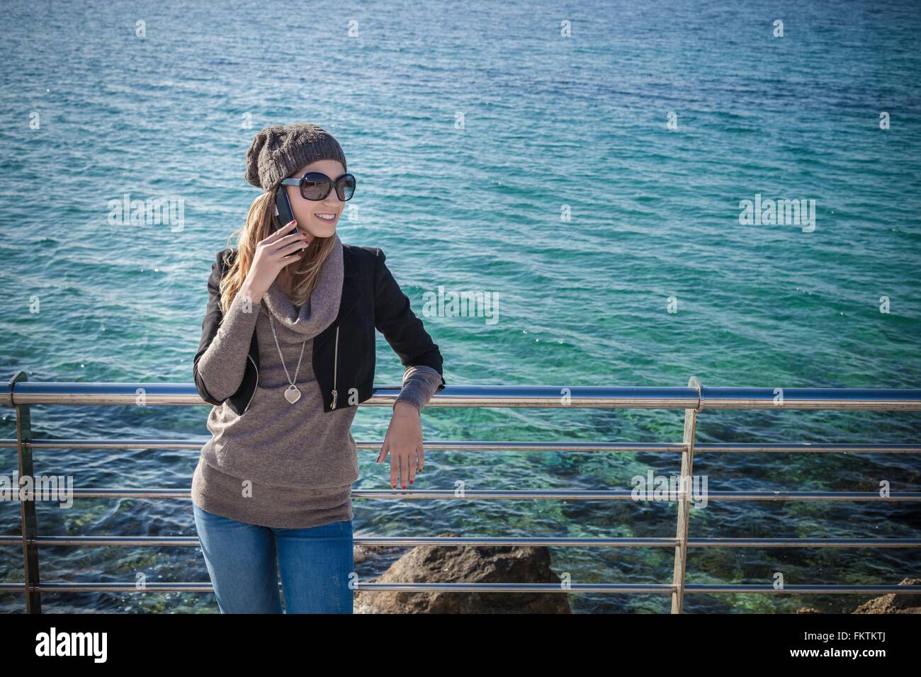 High angle view young woman leaning against railings using smartphone ...