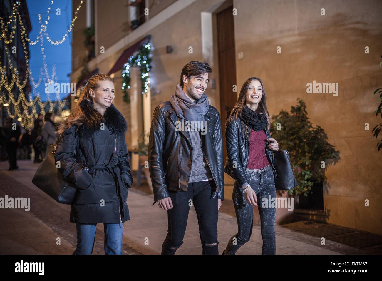 Friends walking down street in the evening smiling Stock Photo - Alamy