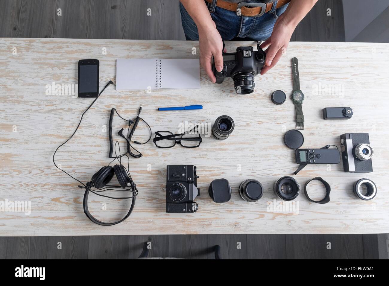 Overhead view of male photographer preparing camera on studio desk ...