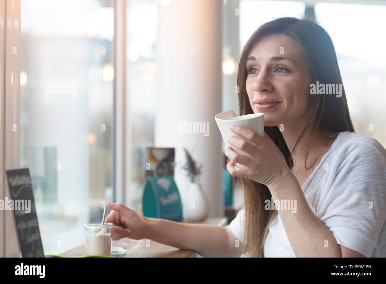 Young woman gazing out through cafe window Stock Photo - Alamy