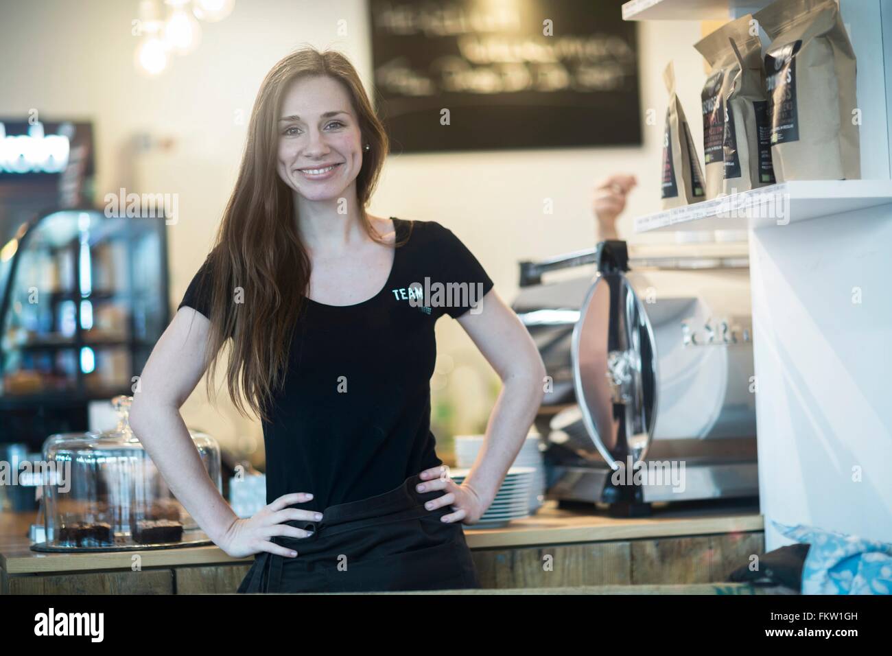 Portrait of young female waitress behind kitchen counter in cafe Stock ...
