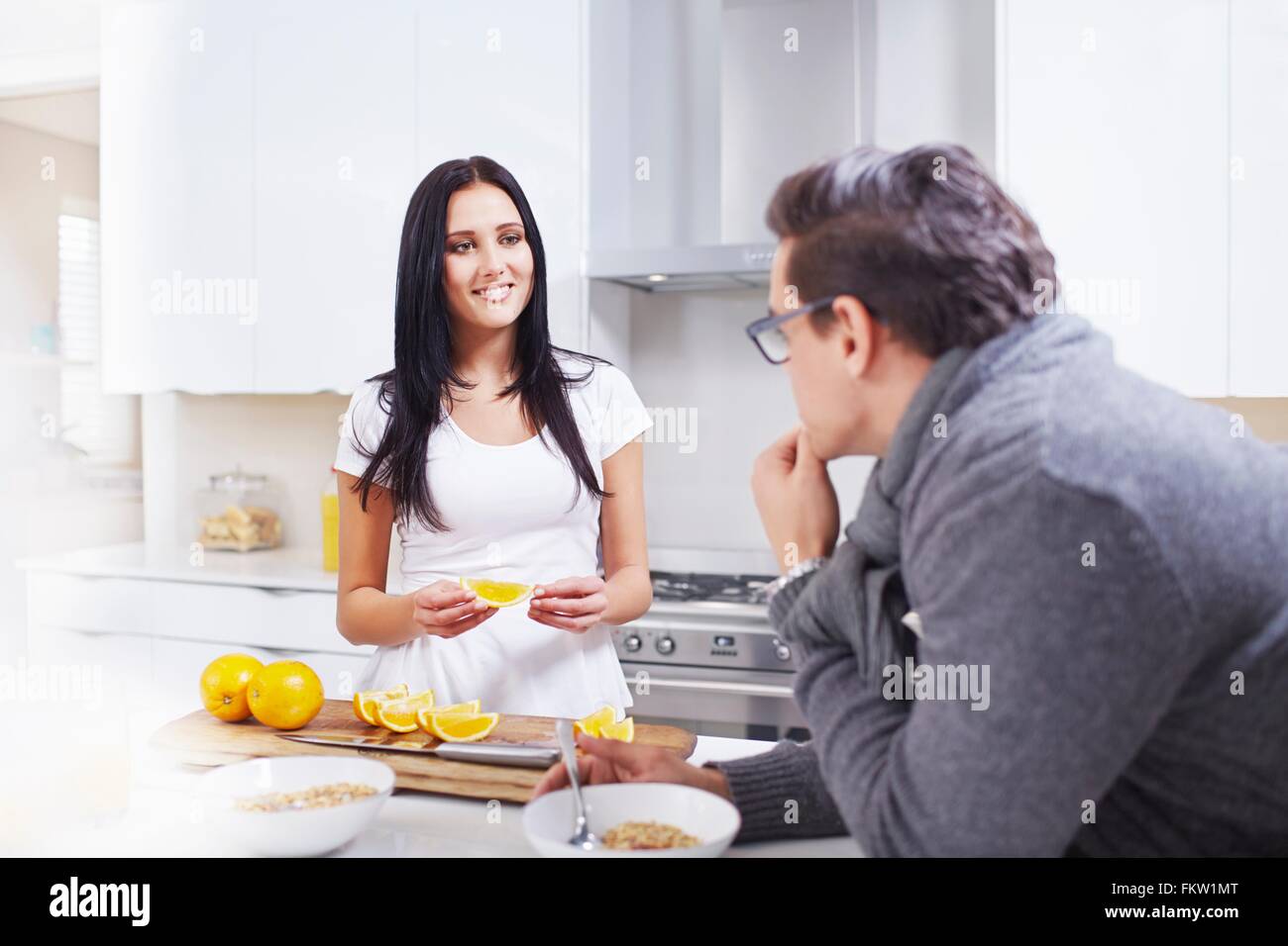 Young couple eating breakfast at kitchen counter Stock Photo - Alamy