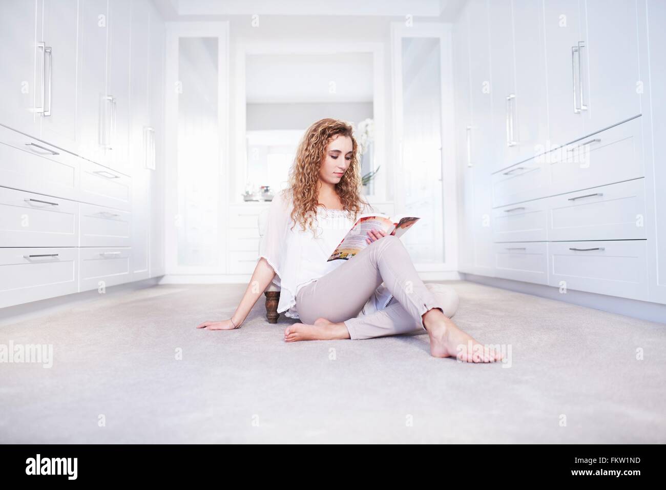 Young woman sitting on floor reading a book in bedroom Stock Photo - Alamy