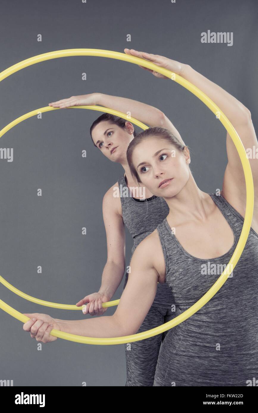 Young women practising with hula hoop, grey background Stock Photo - Alamy