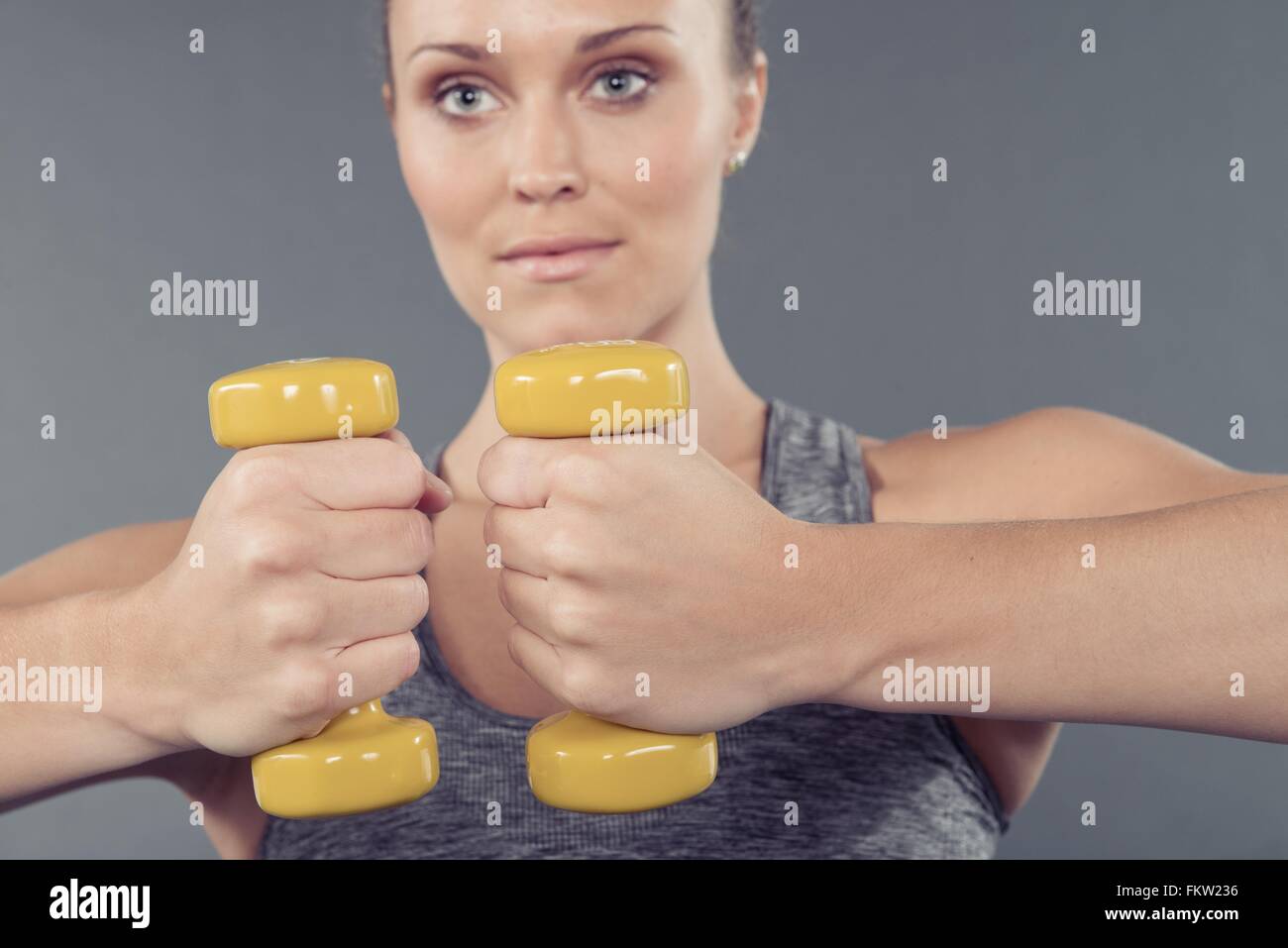 Young woman working out with dumbbells, grey background Stock Photo - Alamy