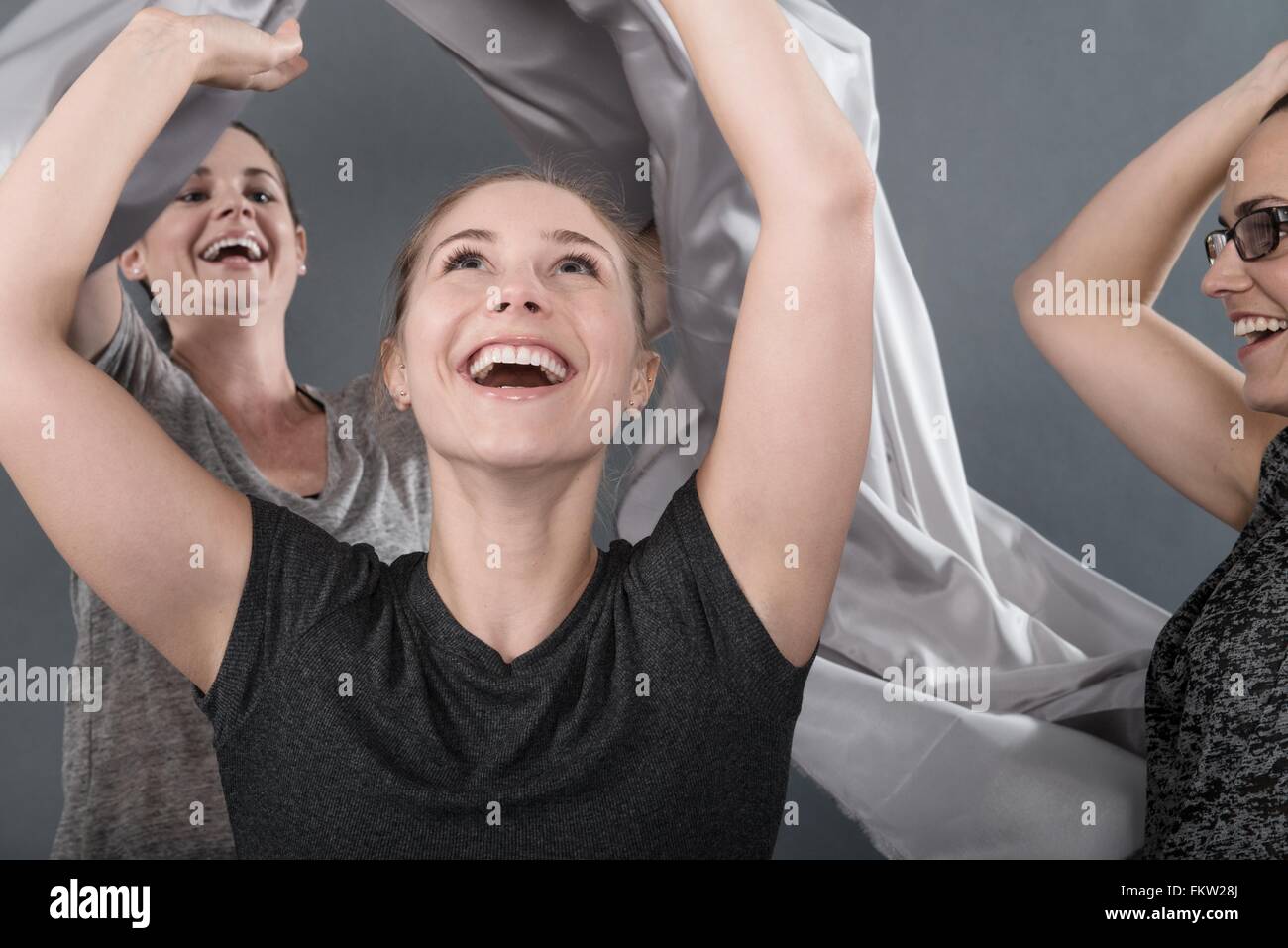 Young women holding cloth over head, grey background Stock Photo - Alamy
