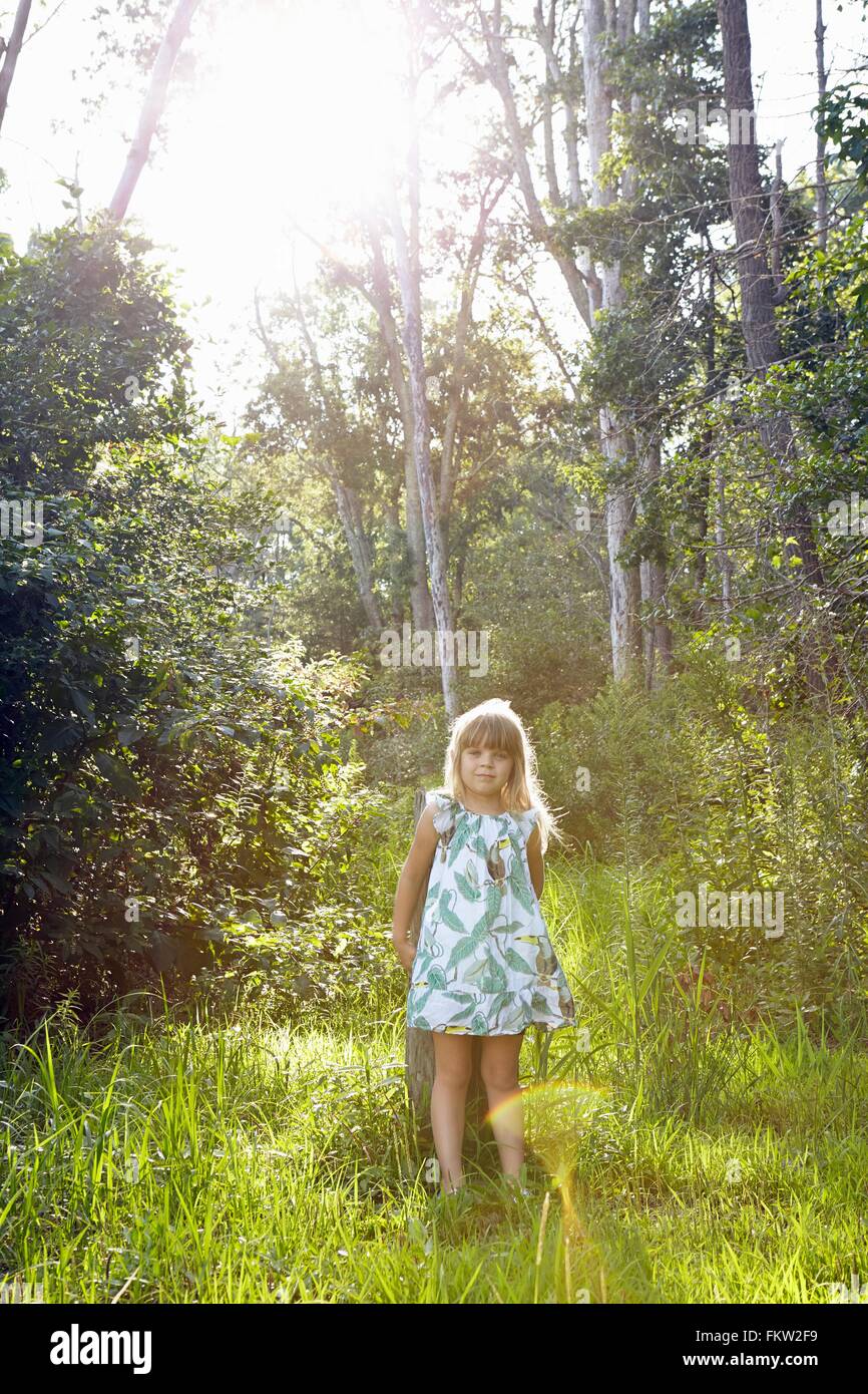 Girl standing against tree in forest Stock Photo - Alamy