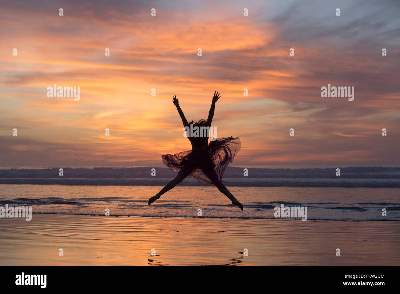Young female dancer wearing chiffon dress, dancing, in mid air, on ...