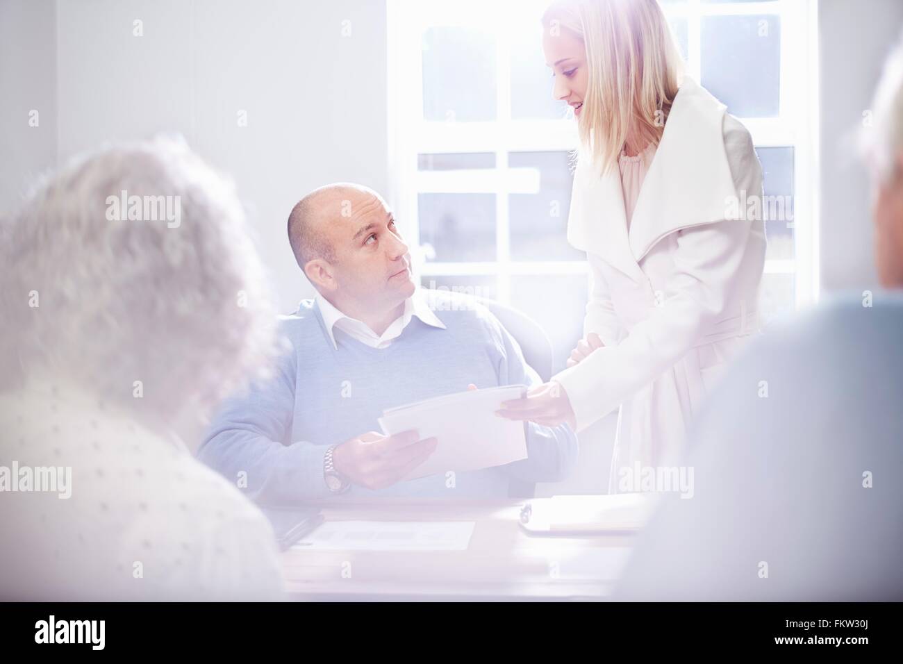Secretary handing paperwork to businessman in office Stock Photo - Alamy