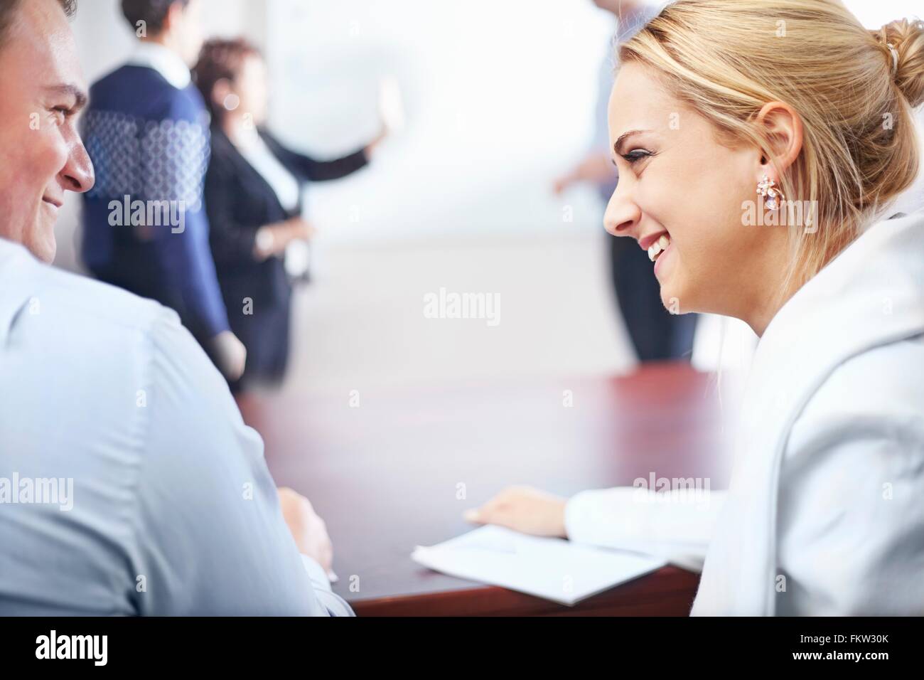 Over shoulder view colleagues in conference room face to face smiling ...