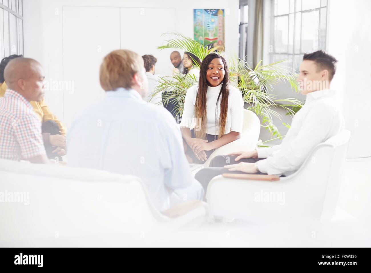 Colleagues in fice sitting chatting, smiling Stock Photo - Alamy