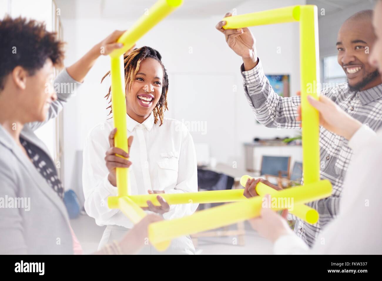 Colleagues in team building task holding yellow rubes smiling Stock ...