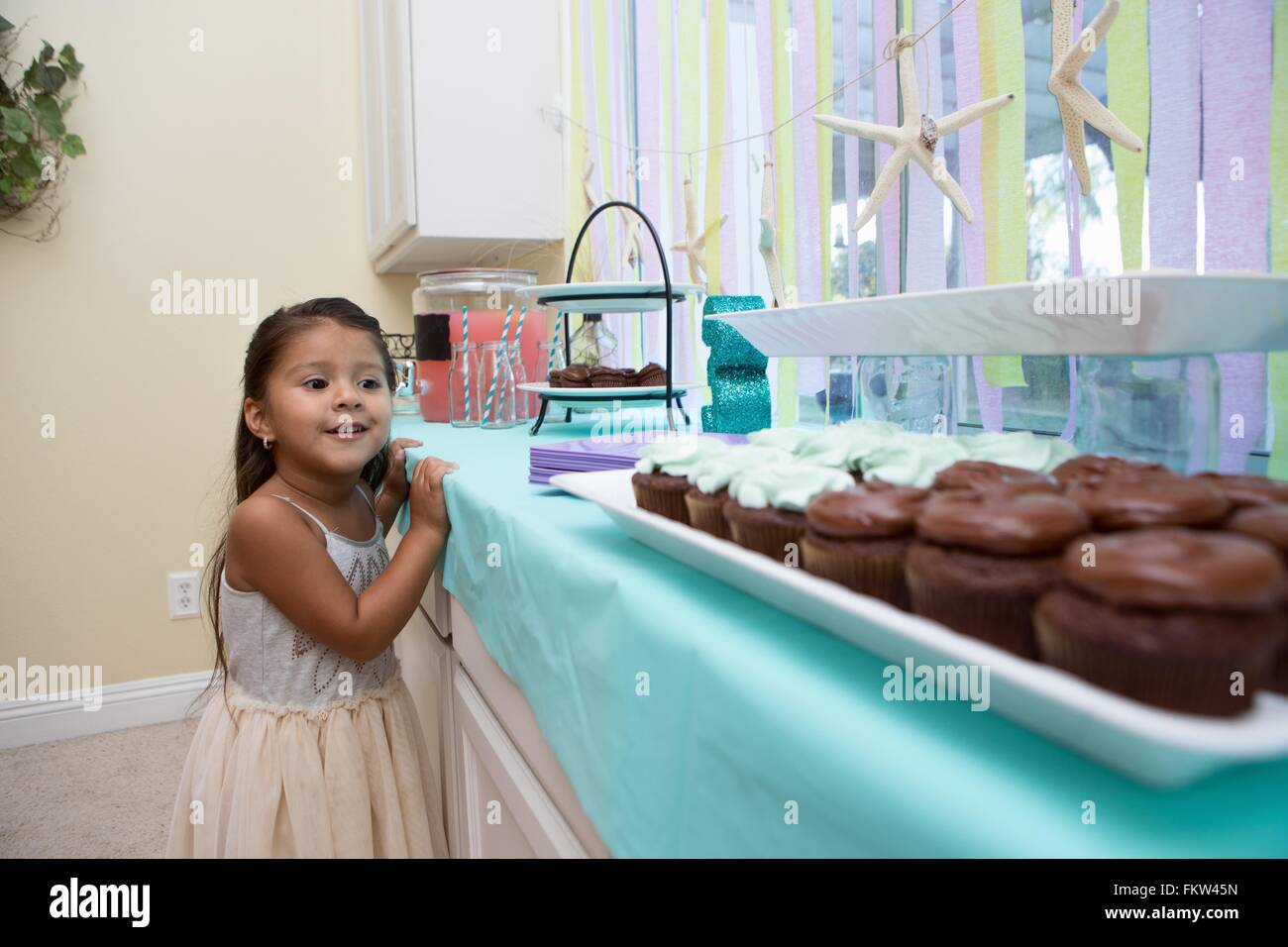 Young girl looking longingly at cakes on kitchen work surface Stock ...