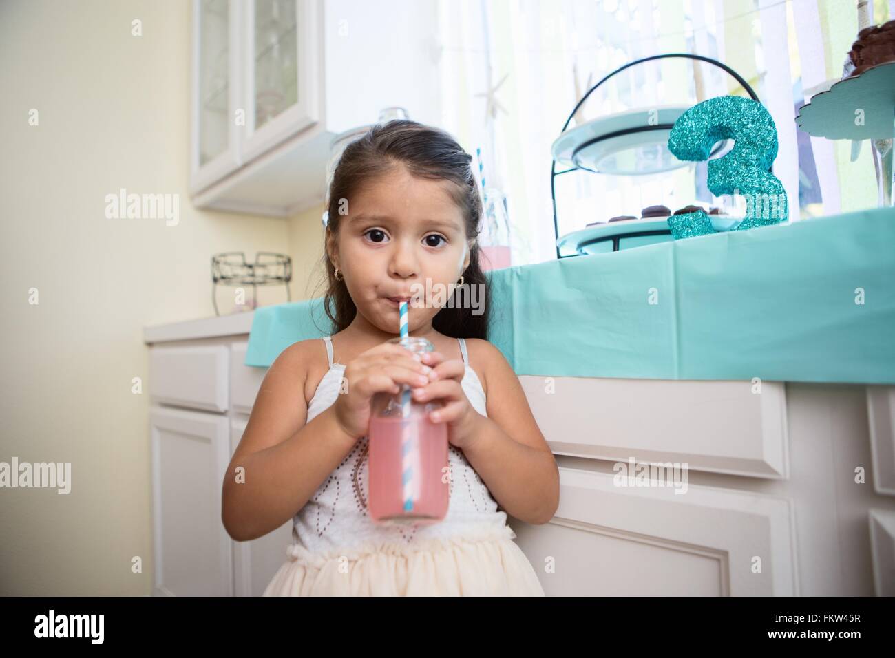 Portrait Of Young Girl Drinking Drink Through Straw At Birthday Party