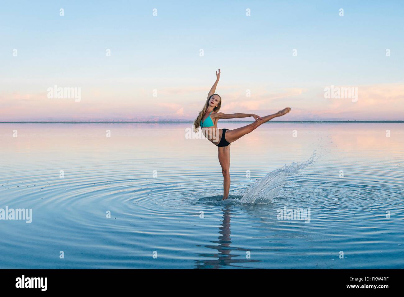 Female ballet dancer poised on one leg in lake, Bonneville Salt Flats ...