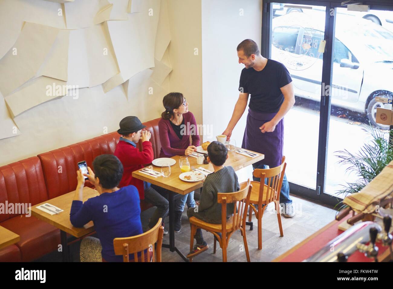 Waiter serving lunch in restaurant to family with boys Stock Photo - Alamy