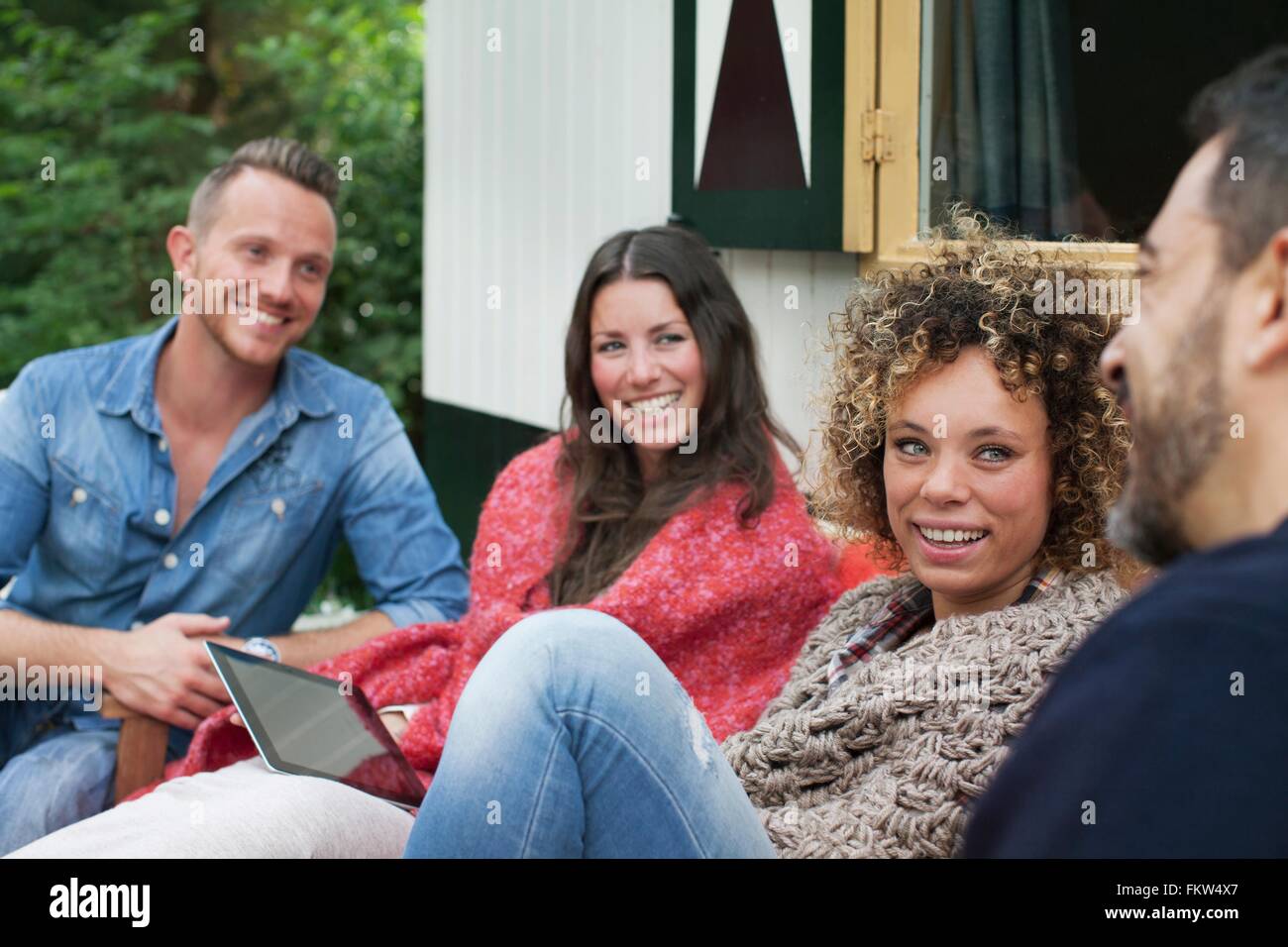 Four adult friends chatting outside cabin Stock Photo - Alamy