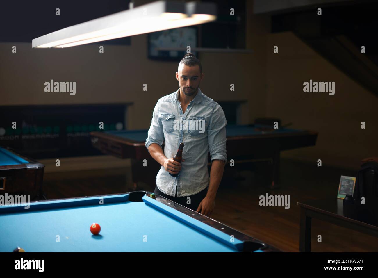 Man with beer standing at pool table Stock Photo - Alamy