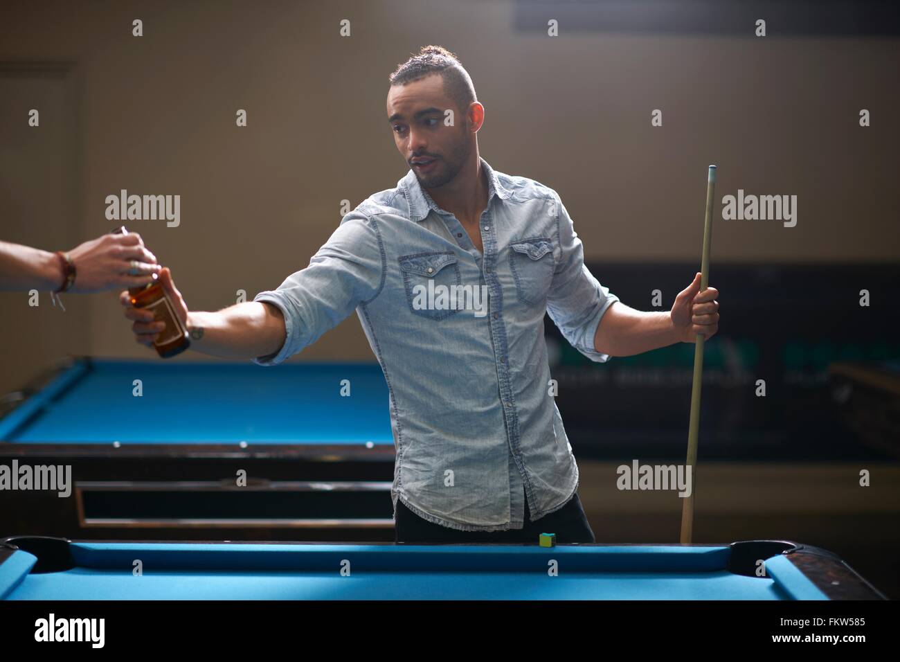 Man taking beer from friend at pool table Stock Photo - Alamy