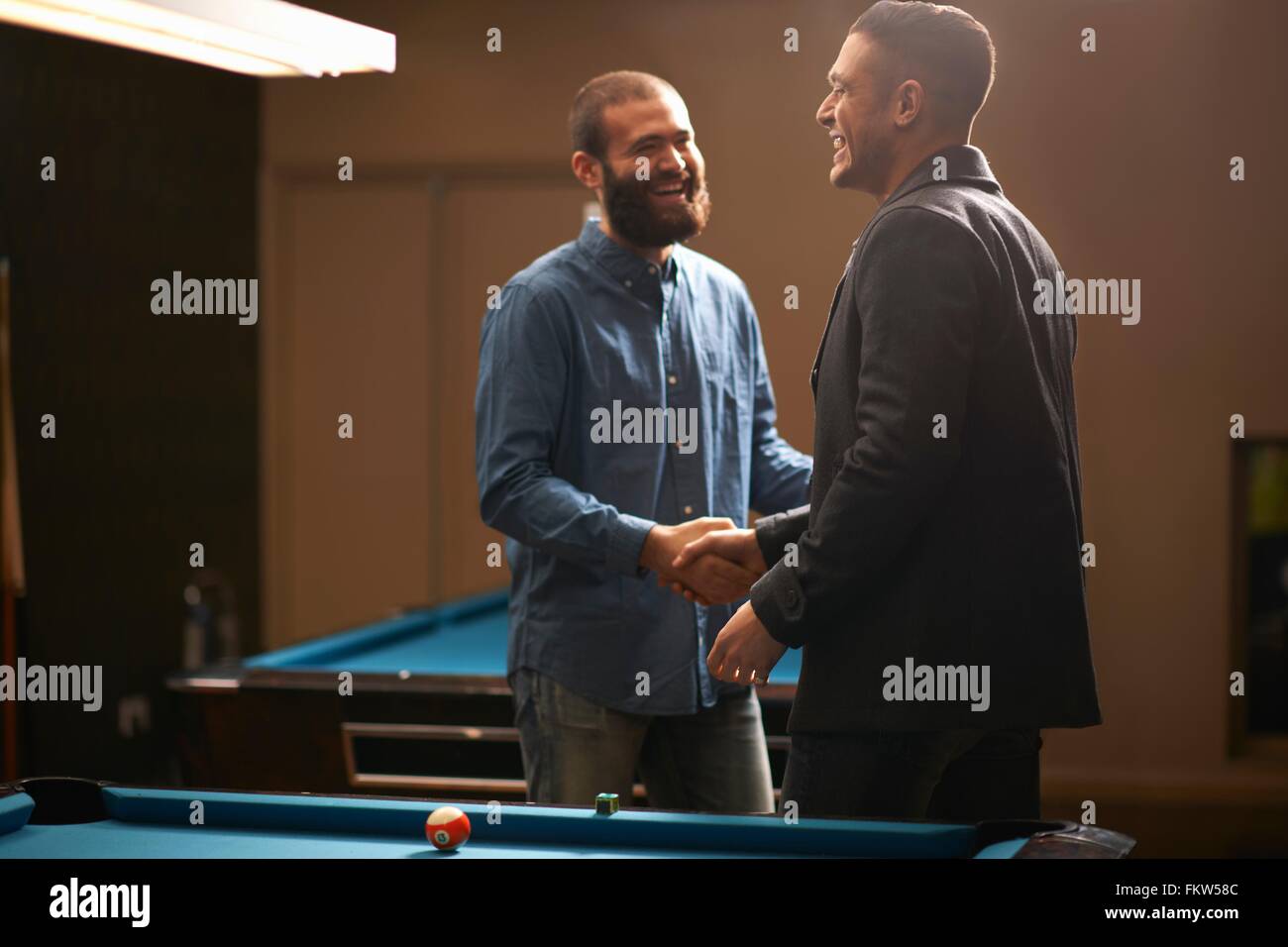 Men shaking hands at pool table Stock Photo - Alamy