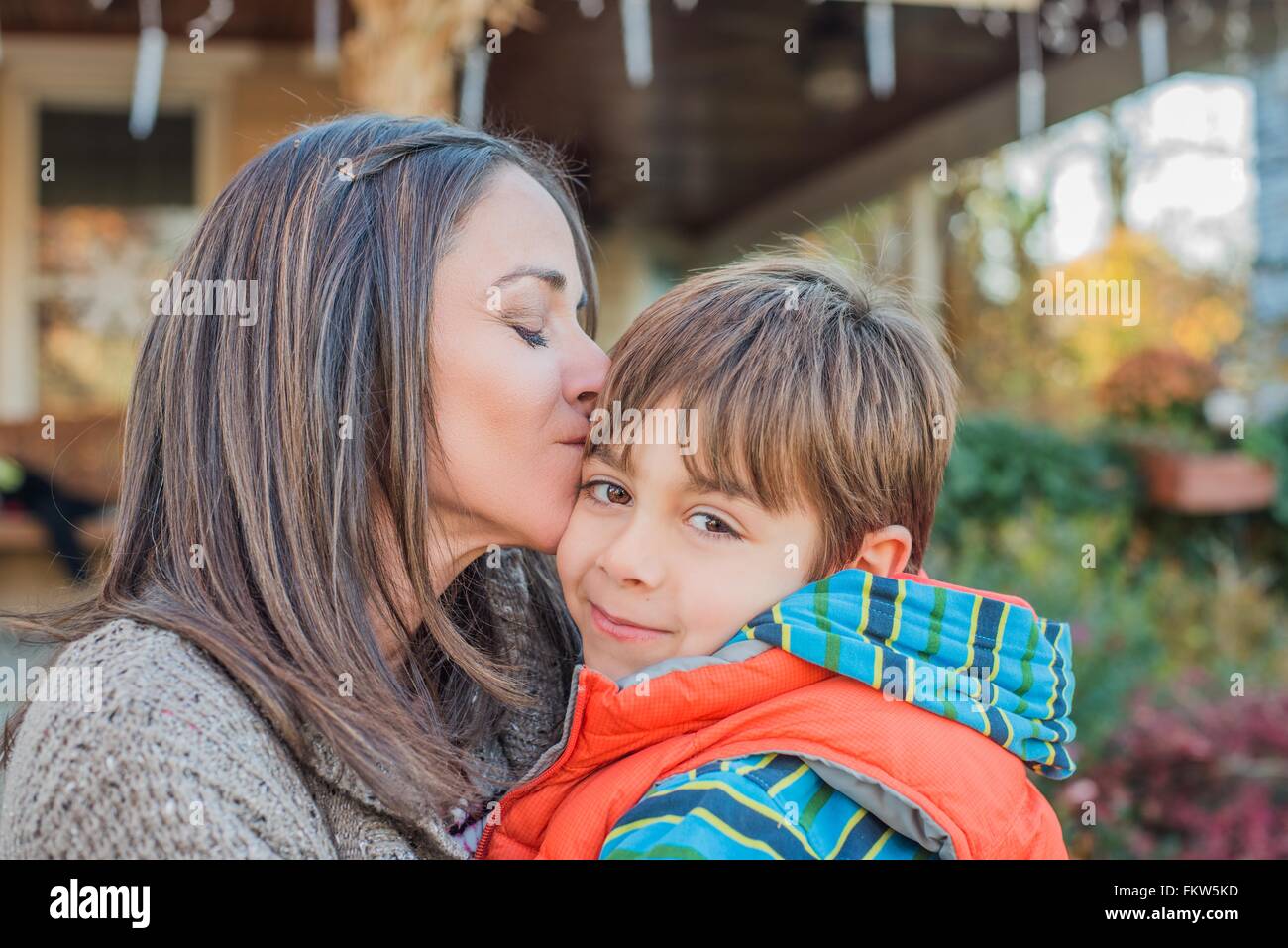 Mother hugging and kissing son in front of house Stock Photo - Alamy
